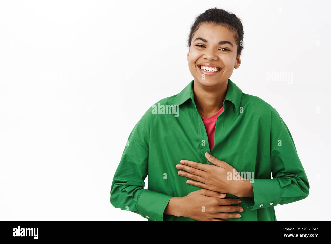 Smiling girl, laughs and looks happy, holds hands on belly, express ...