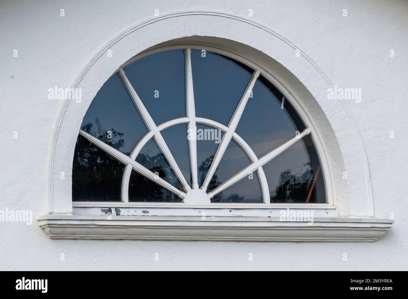 A closeup of a semi circular window with sunburst design on a white ...