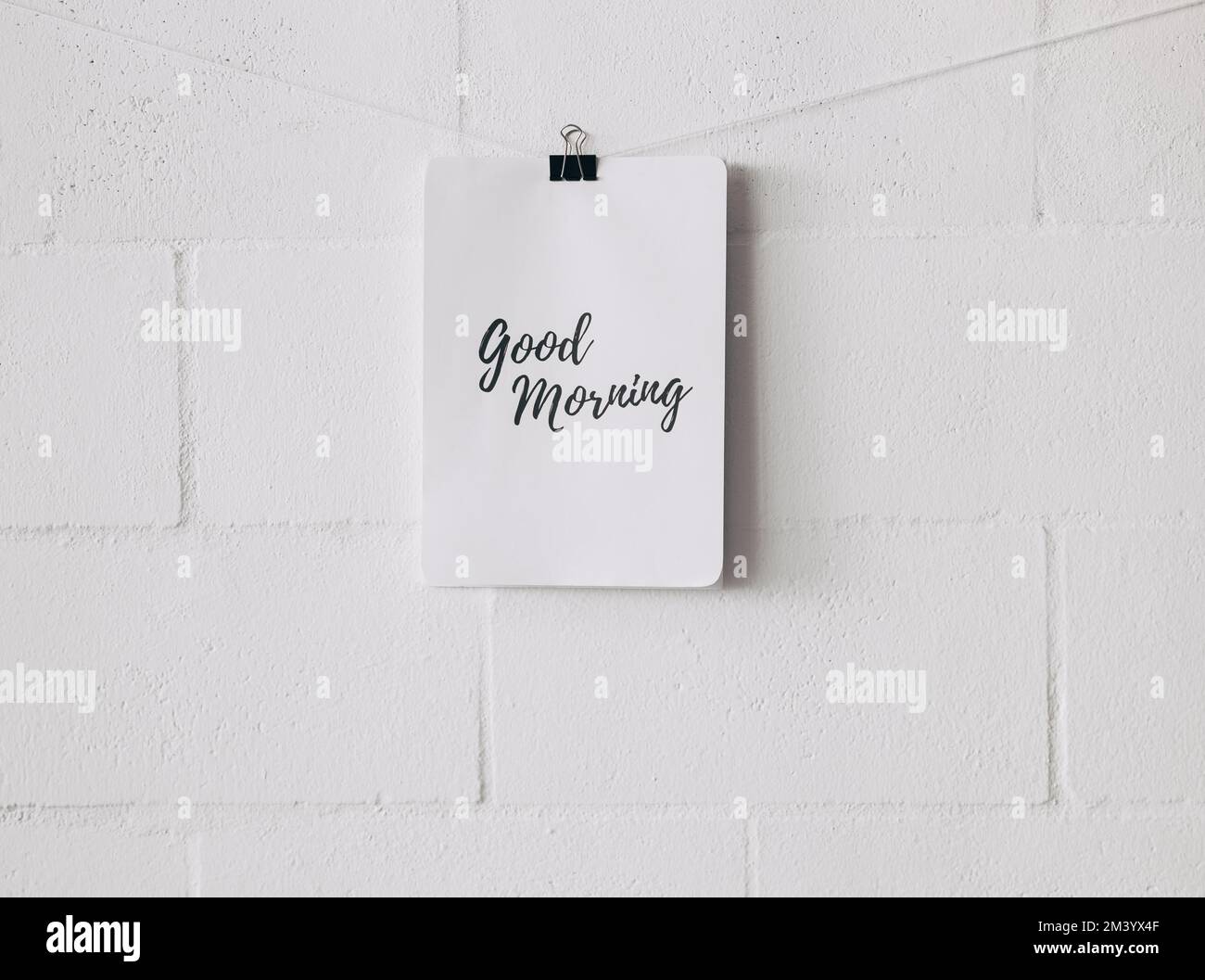 Good morning tag attach on string with bulldog paper clip against white ...