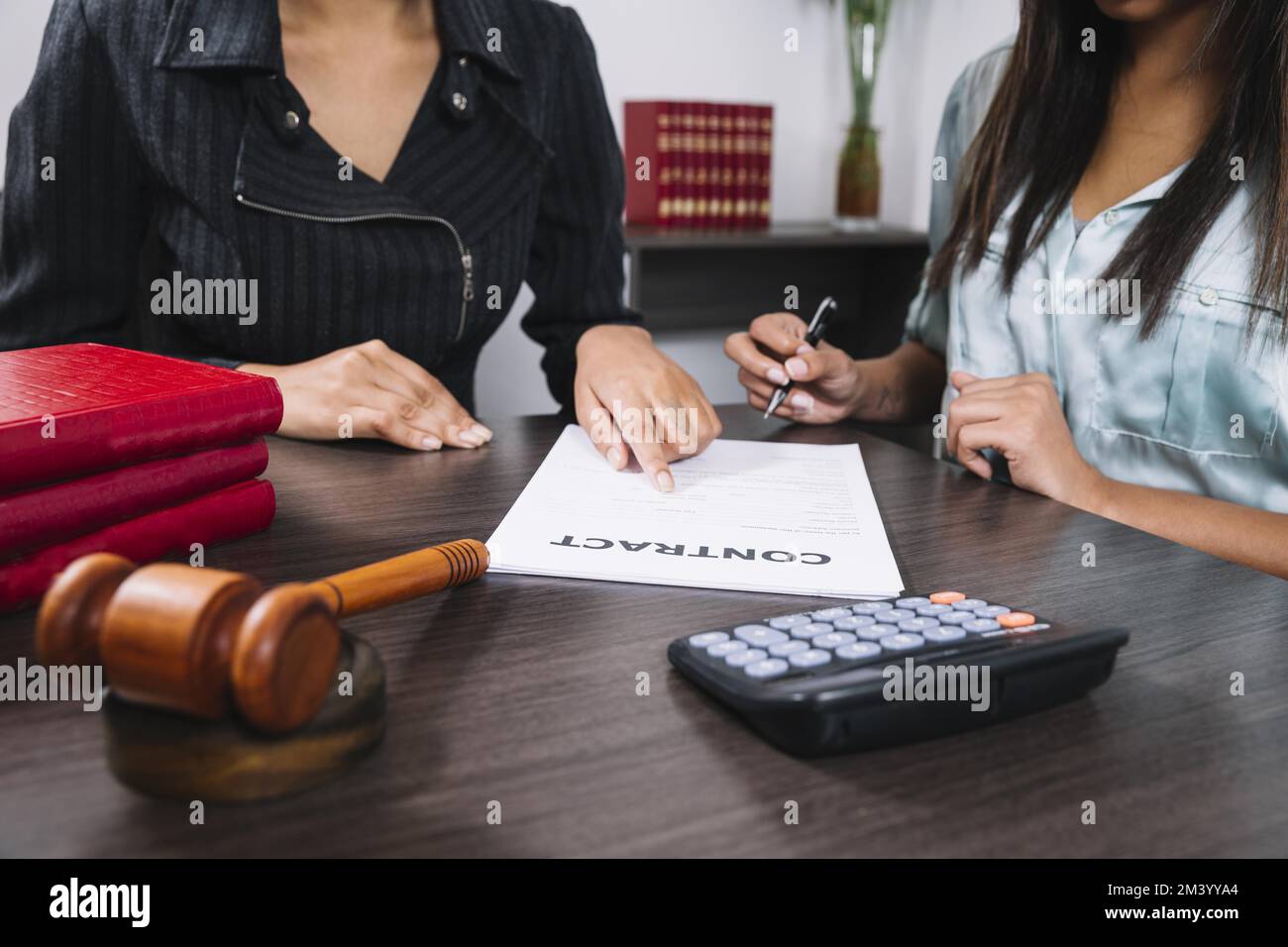 Black woman pointing document near lady with pen table with calculator ...