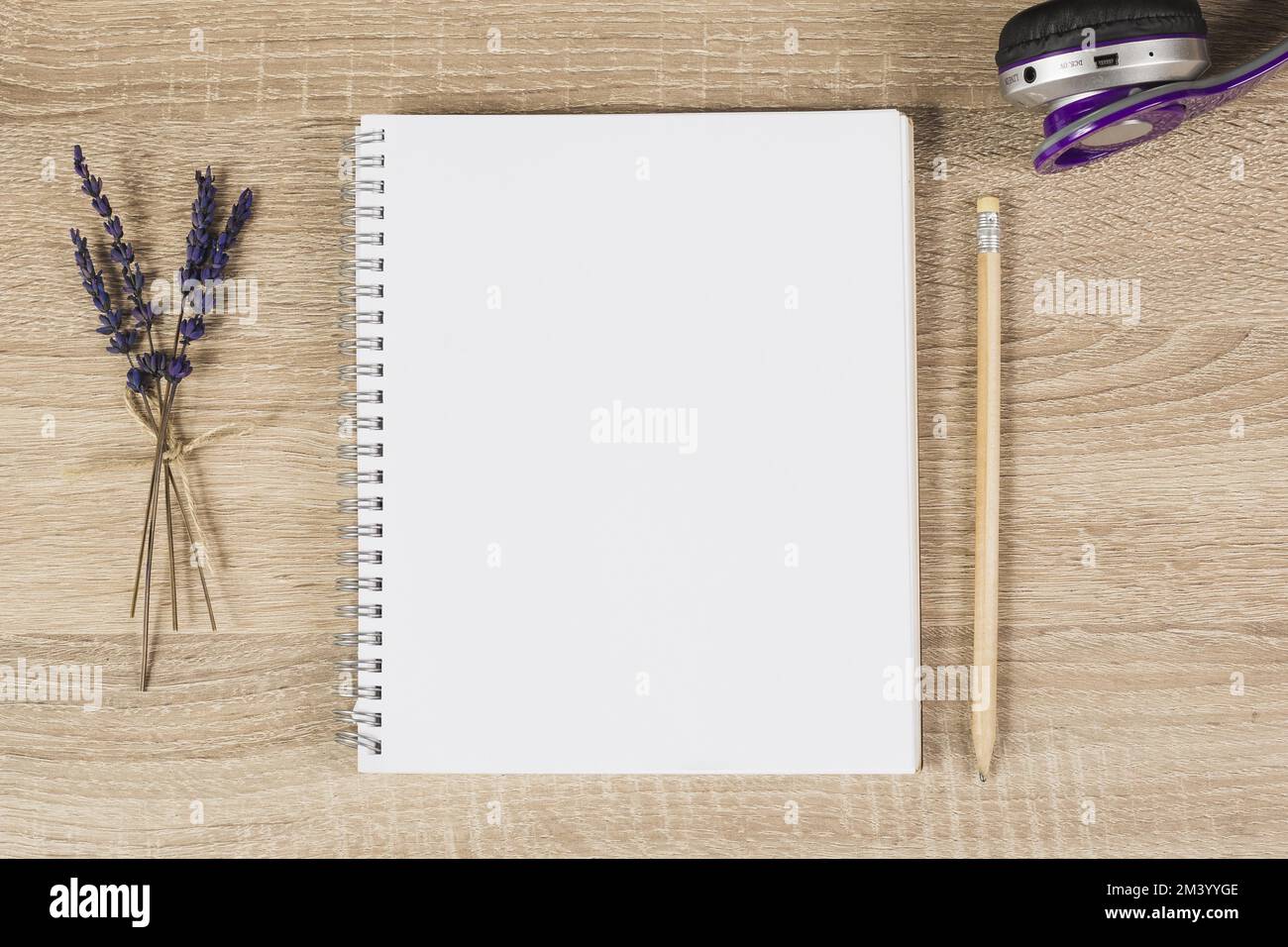 Blank spiral notebook pencil headphone lavender twigs wooden background ...
