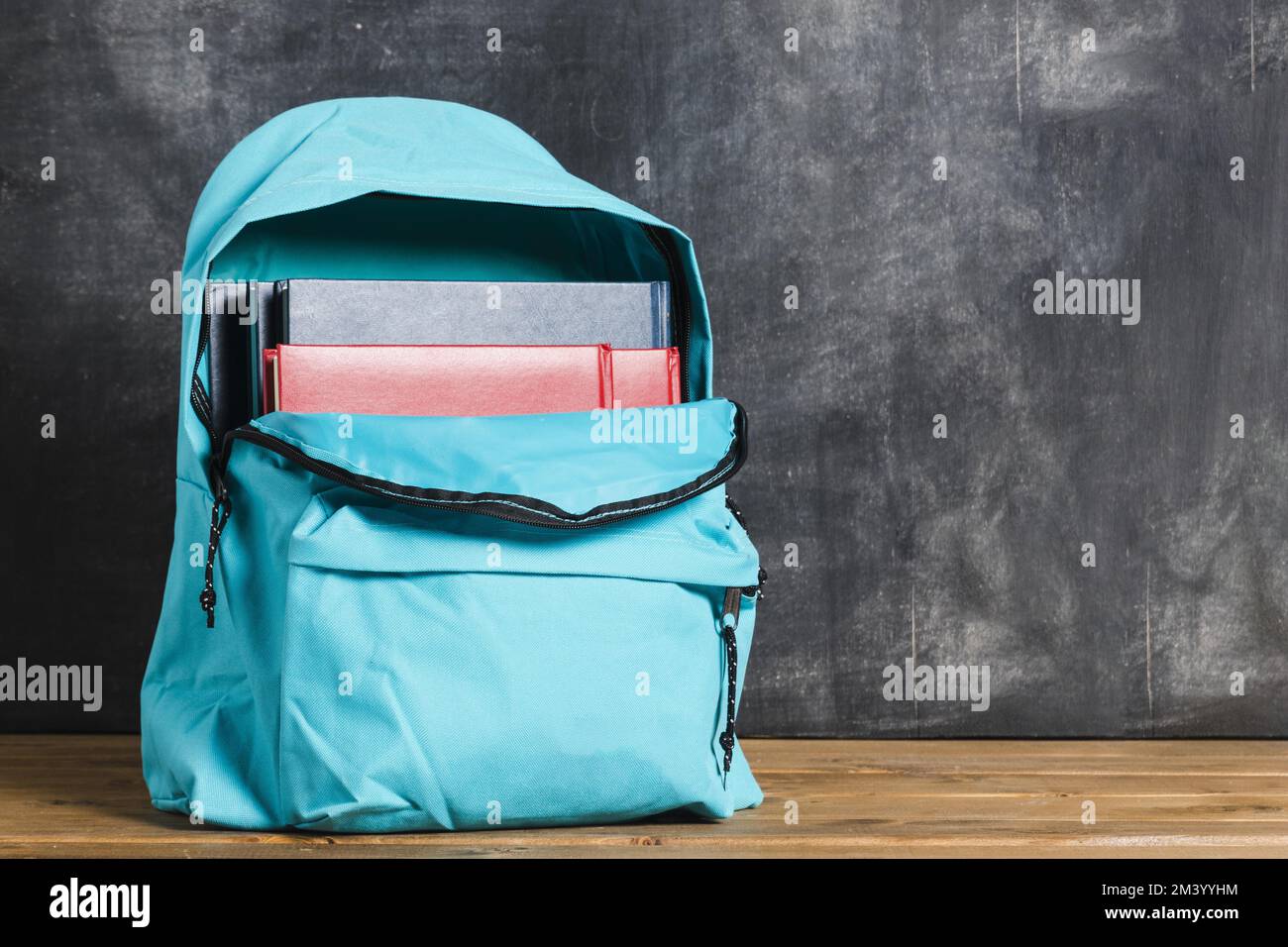 Blue backpack with textbooks Stock Photo - Alamy