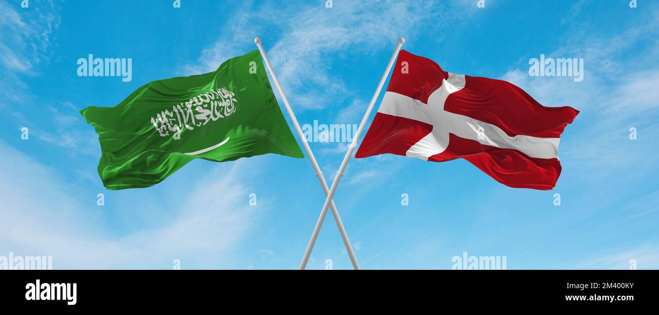 two crossed flags denmark and Saudi Arabia waving in wind at cloudy sky ...