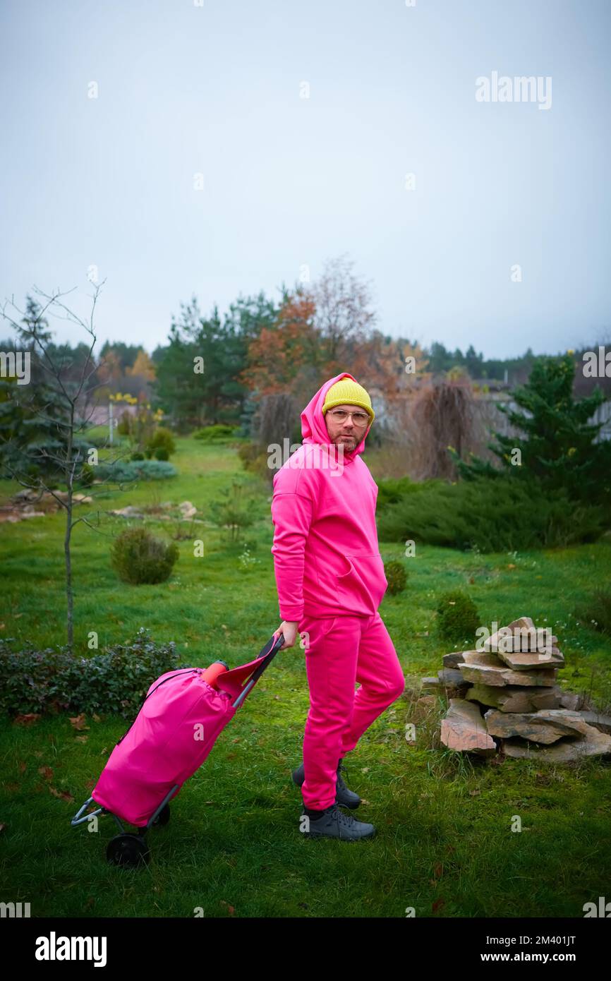 Pink man posing outdoor in pink sport suit with rolling bag. Pink suit ...