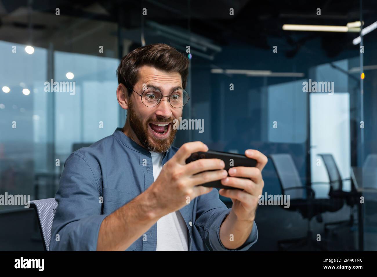 Mature businessman with beard is playing game on smartphone, man is ...