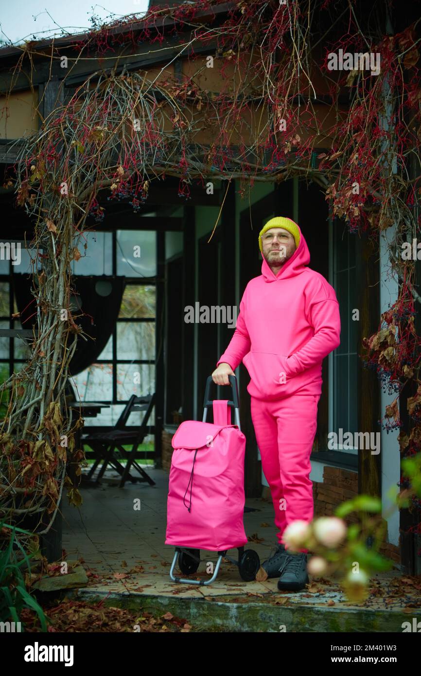 Pink man posing outdoor in pink sport suit with rolling bag. Pink suit ...