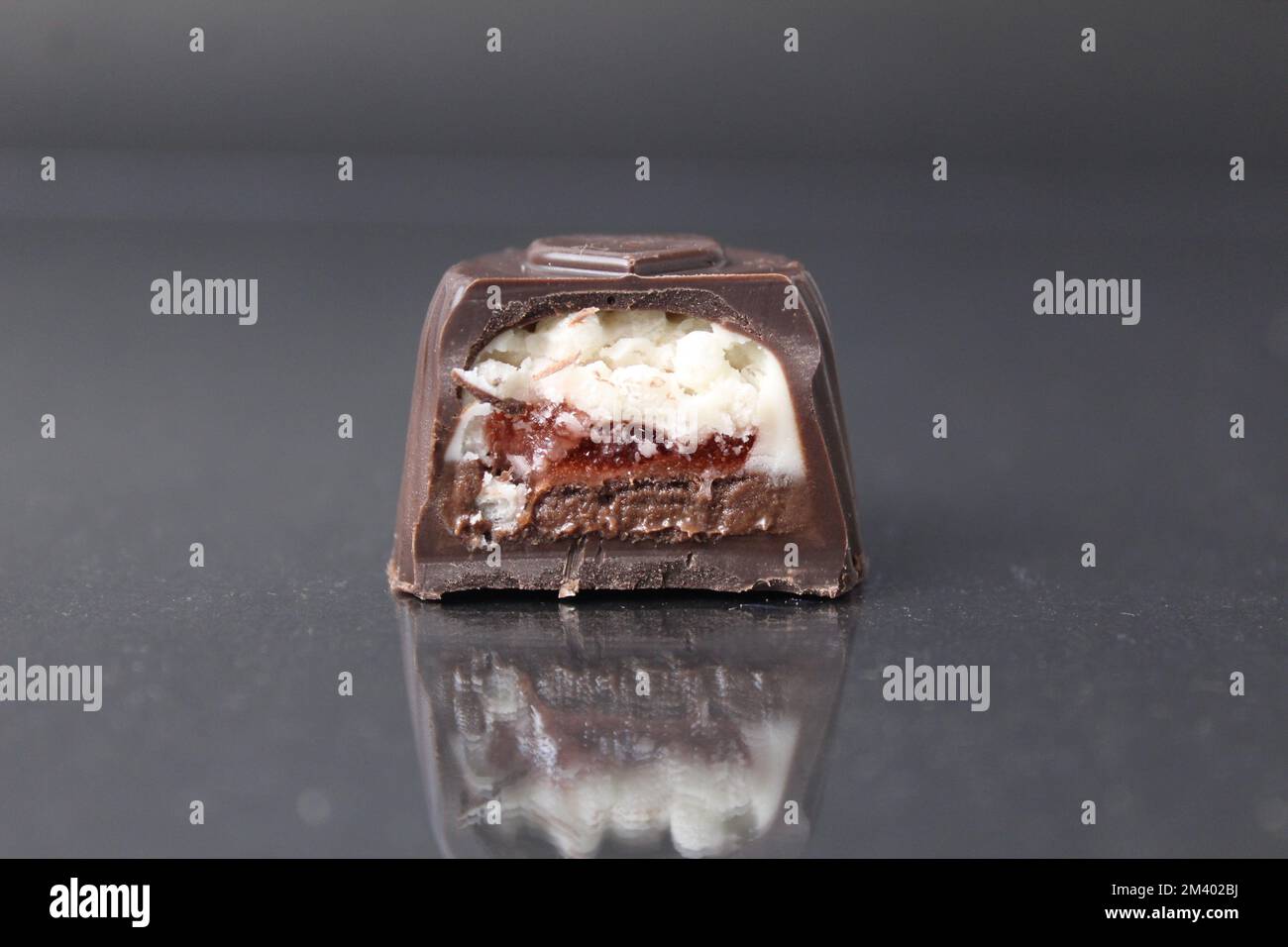 a chocolate candy case creamy slice in a section on a black background ...
