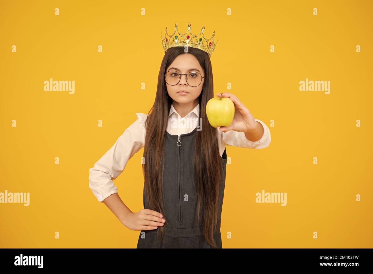 Teen child in queen crown hold apple isolated on yellow background ...
