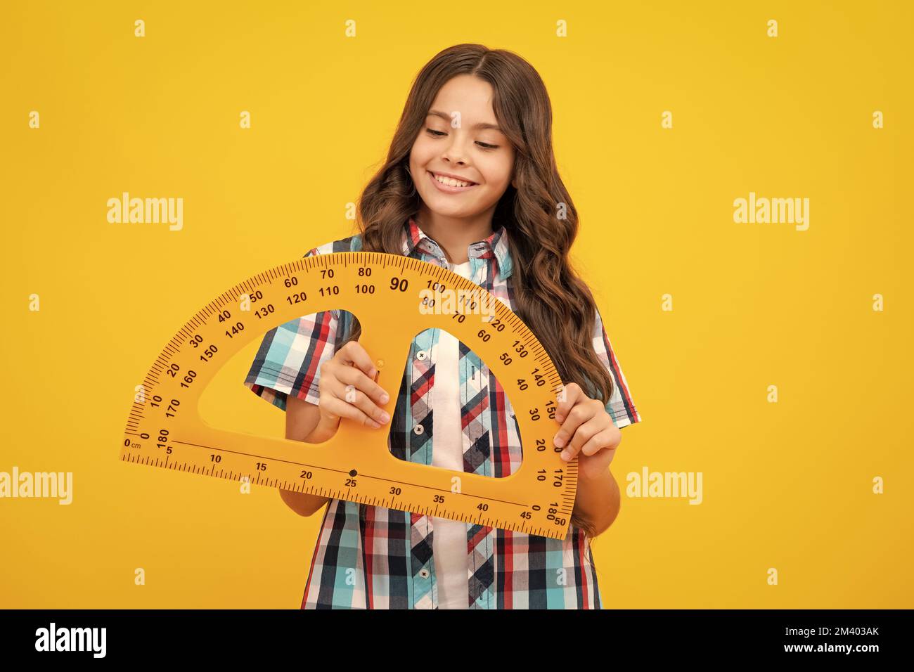 School girl holding measure for geometry lesson, isolated on yellow ...