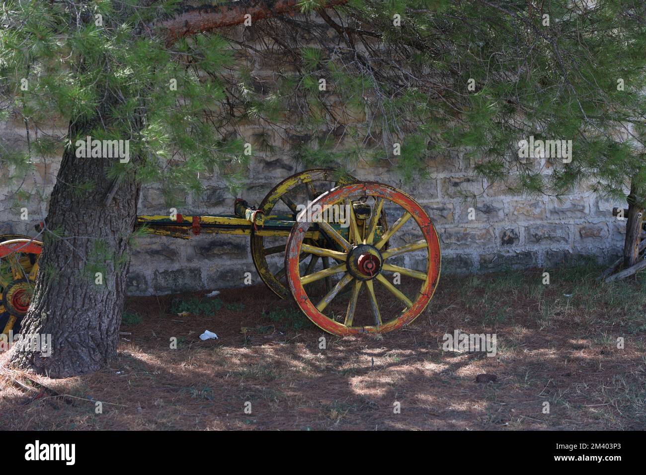 An old and rustic cart wheels under a tree against walls Stock Photo ...