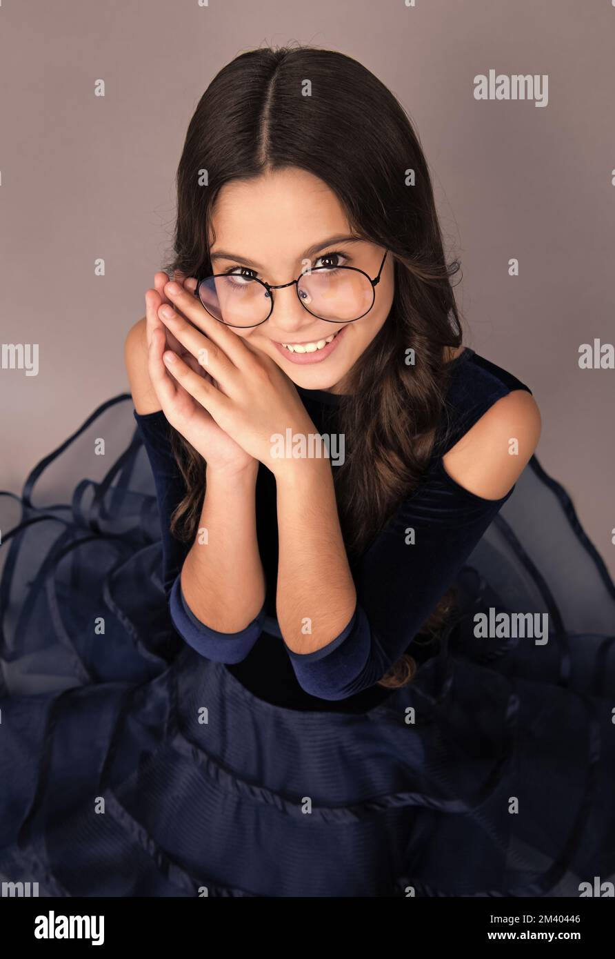 Cute face of teenager girl. Children studio portrait on gray ow ...