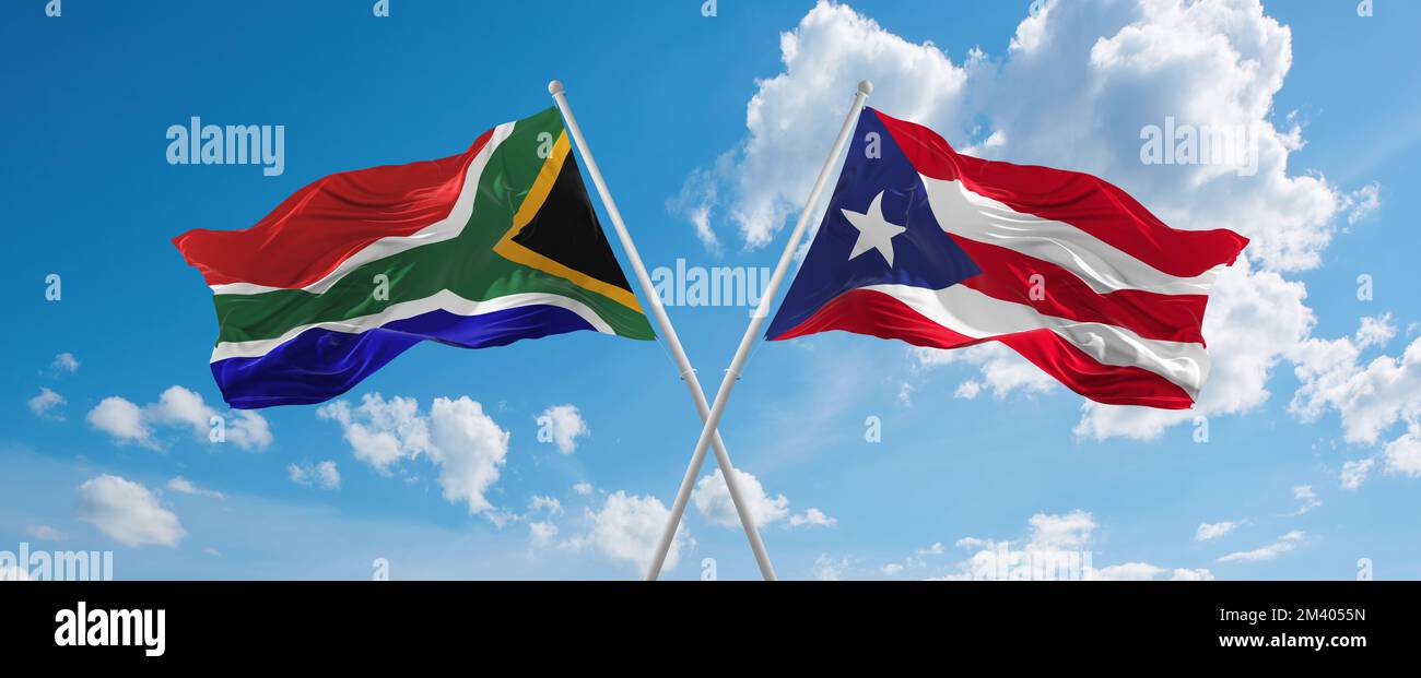 two crossed flags Puerto Rico and South Africa waving in wind at cloudy sky. Concept of ...