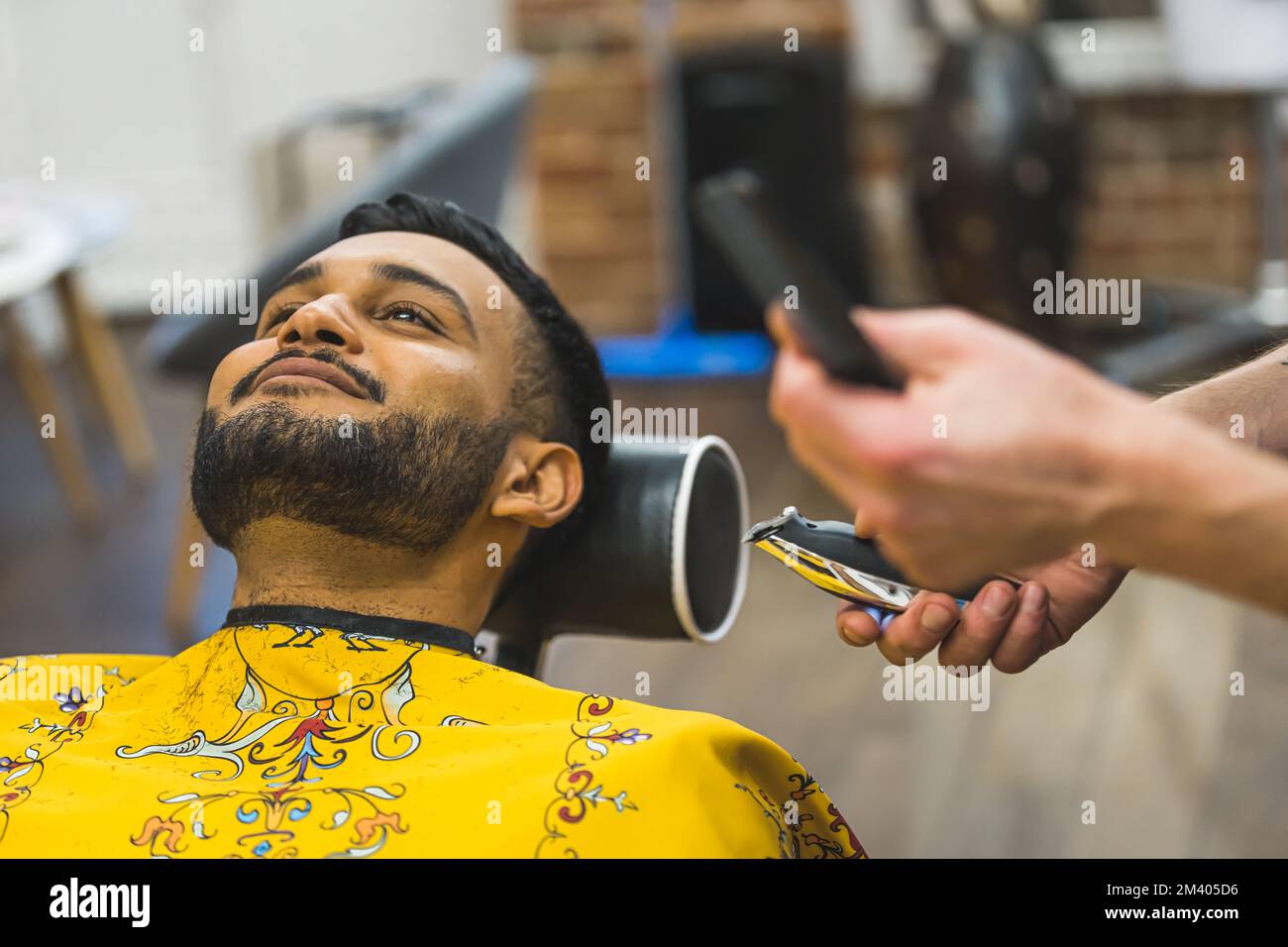 Happy indian client having his beard trimmed by a profssional barber in ...