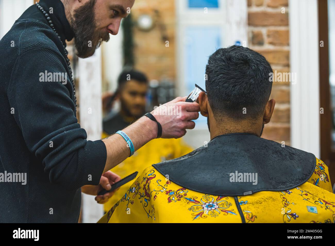 Professional barber gromming his client's hair in a barbershop. Back ...