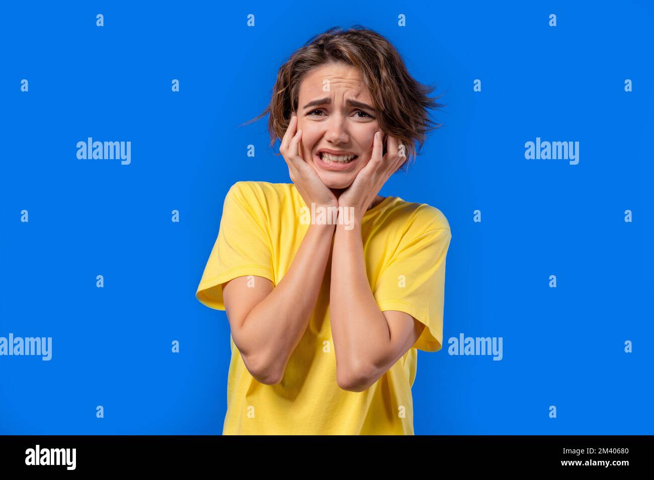 Woman afraid of something and looks into camera with big eyes full of ...
