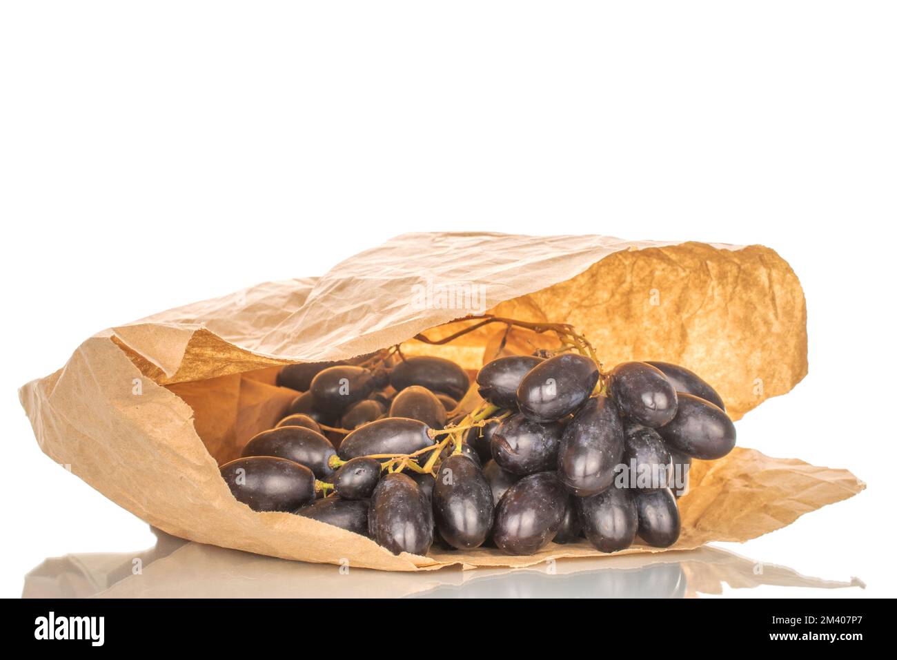 One bunch of black grapes in a paper bag, close-up, isolated on white ...