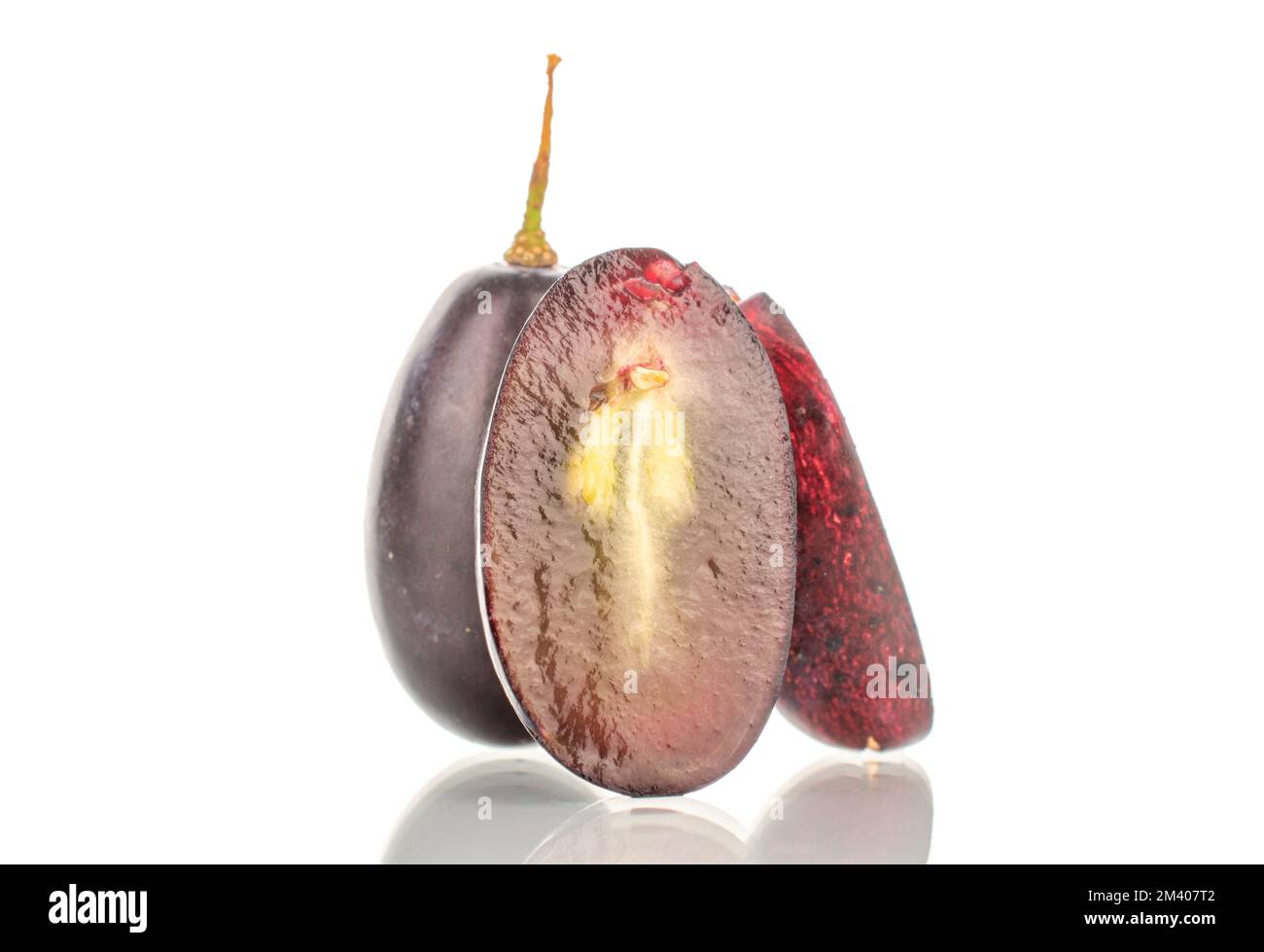 Two halves and one whole berry of black grapes, close-up, isolated on ...