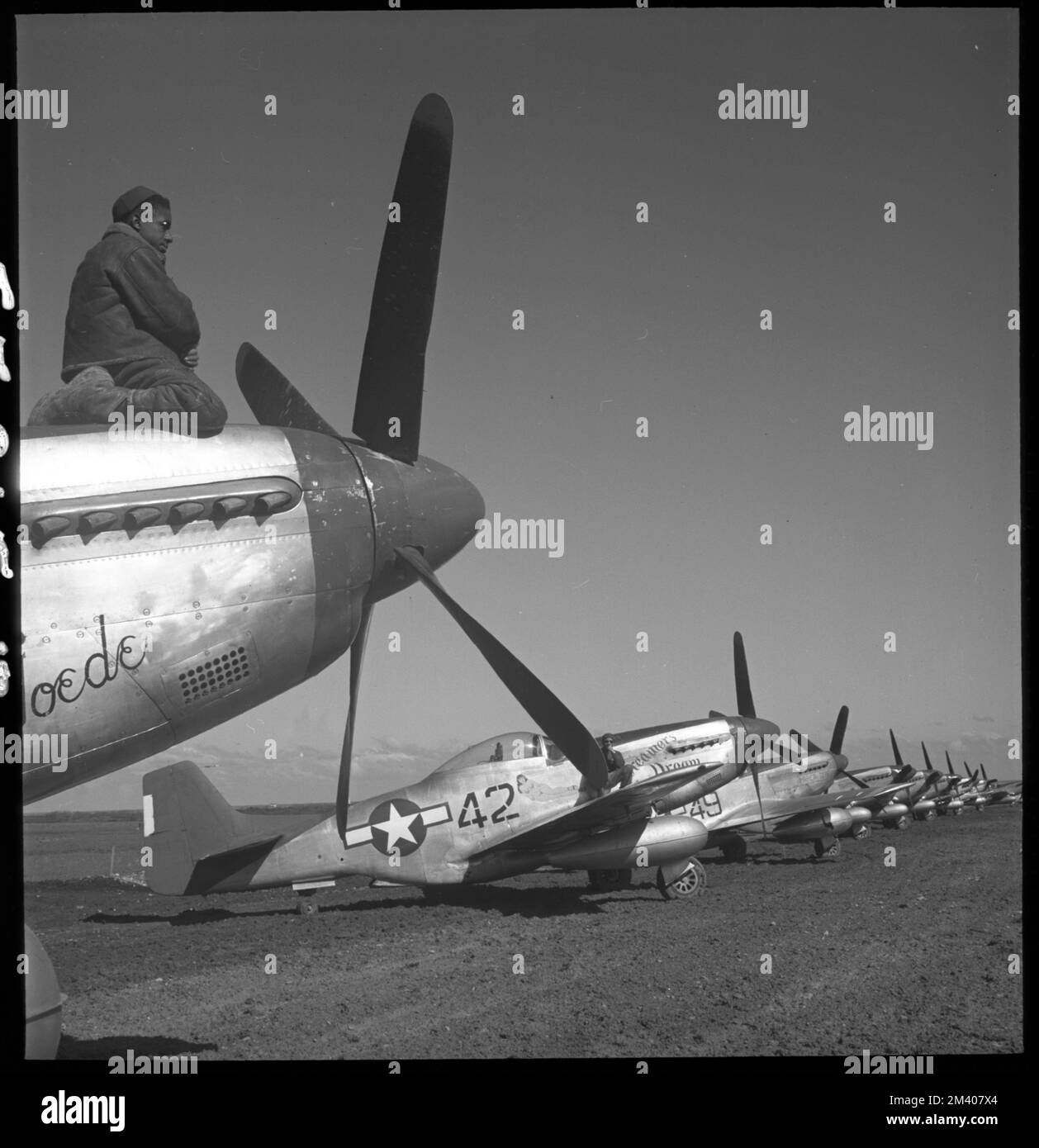 An unidentified Tuskegee airman sitting on top of an airplane, a P-5/D ...