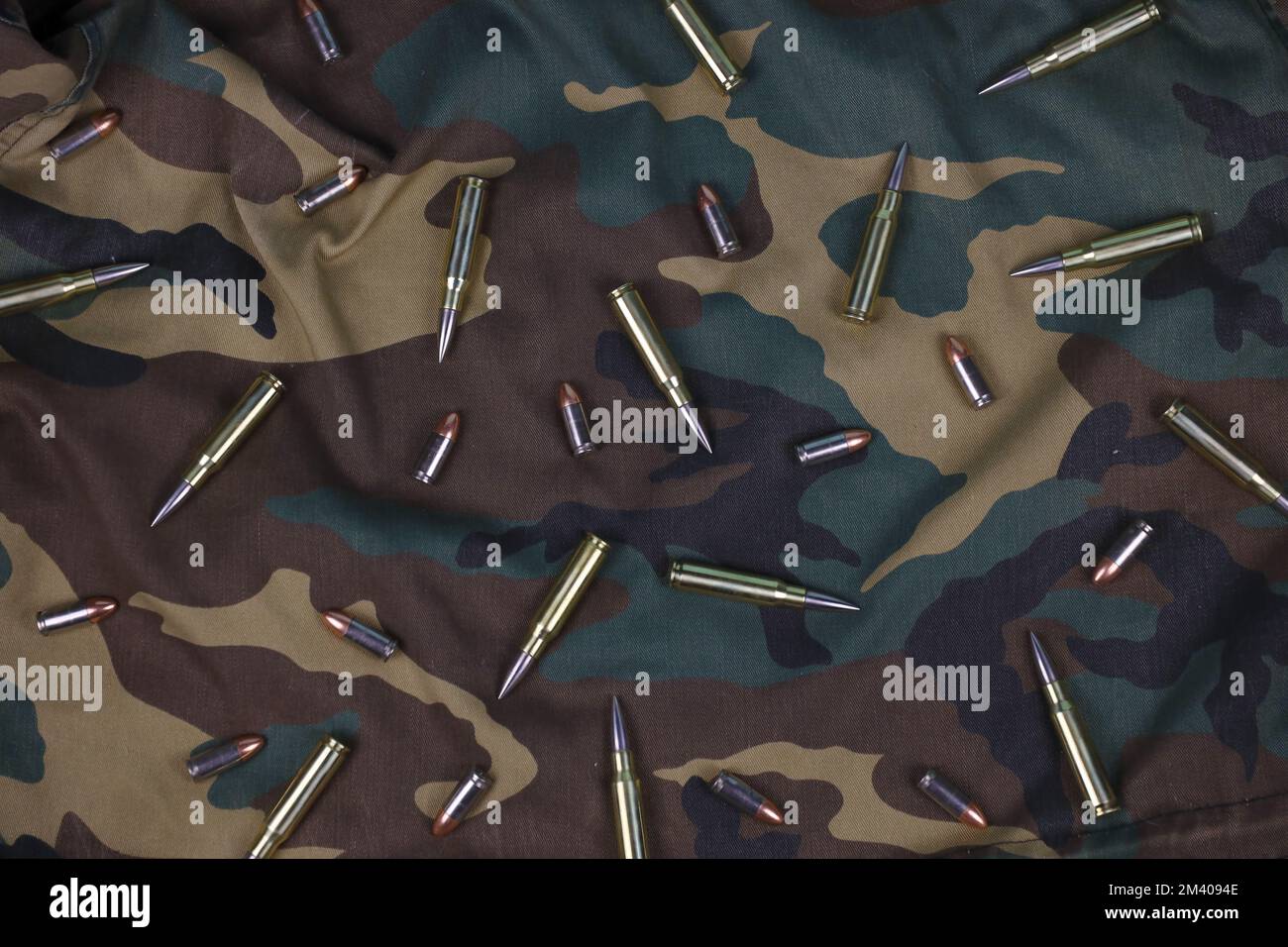 Many rifle bullets and cartridges on dark camouflage background ...