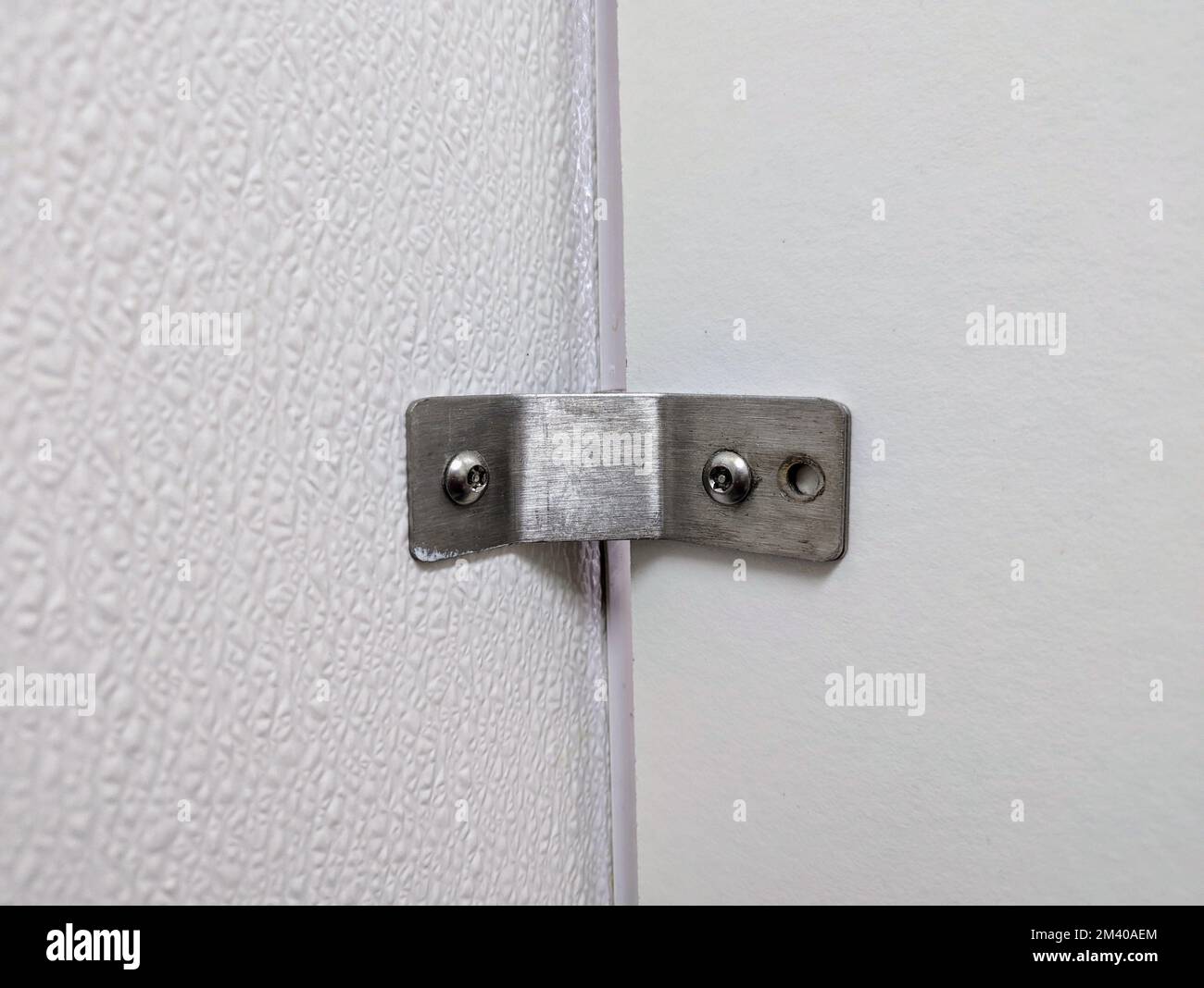 A closeup of Fixing metal bracket on white wall of a public toilet ...