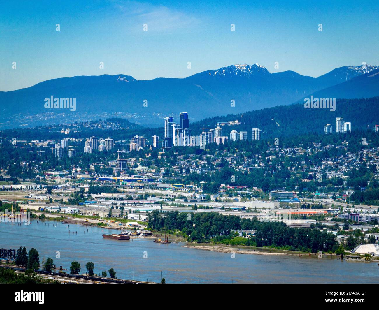A drone shot of Coquitlam cityscape with a river and mountain behind ...