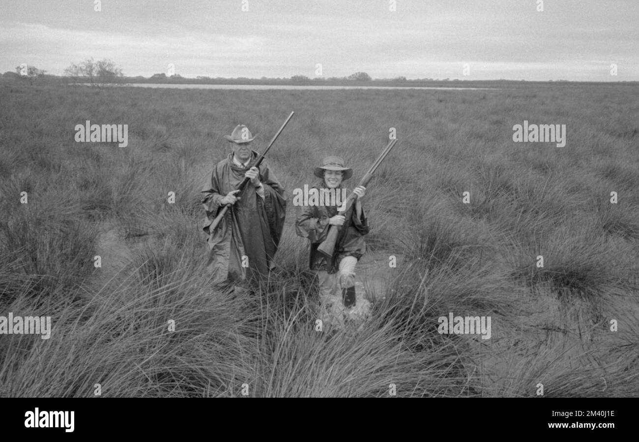 Anne and Tobin Armstrong walking through field, carrying shotguns ...