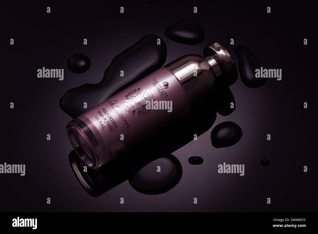 A dark shot of a wet perfume bottle isolated on a black background ...