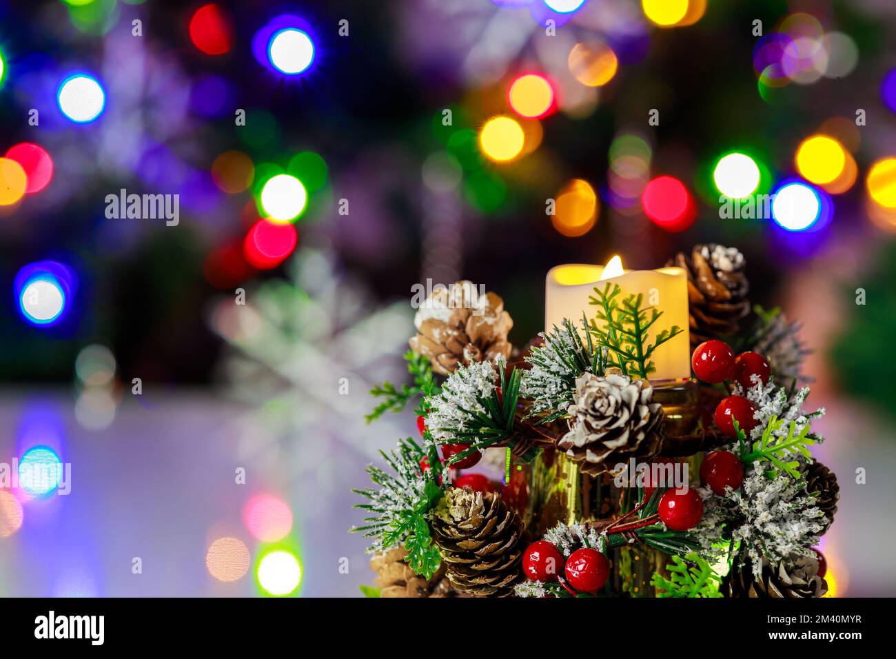Red berries and a burning candle create a festive atmosphere at ...