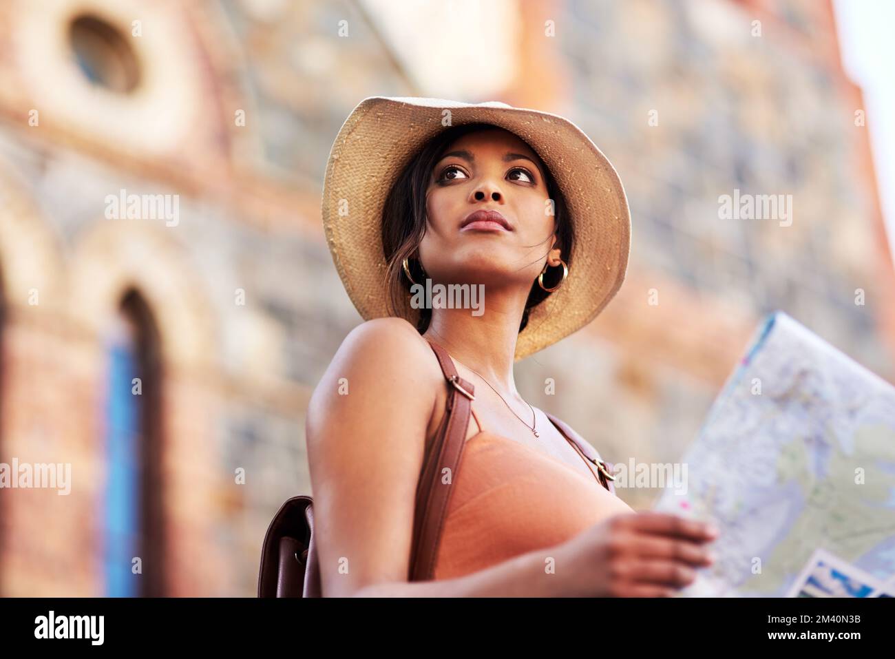 Roaming around in the city. an attractive young woman holding a map ...