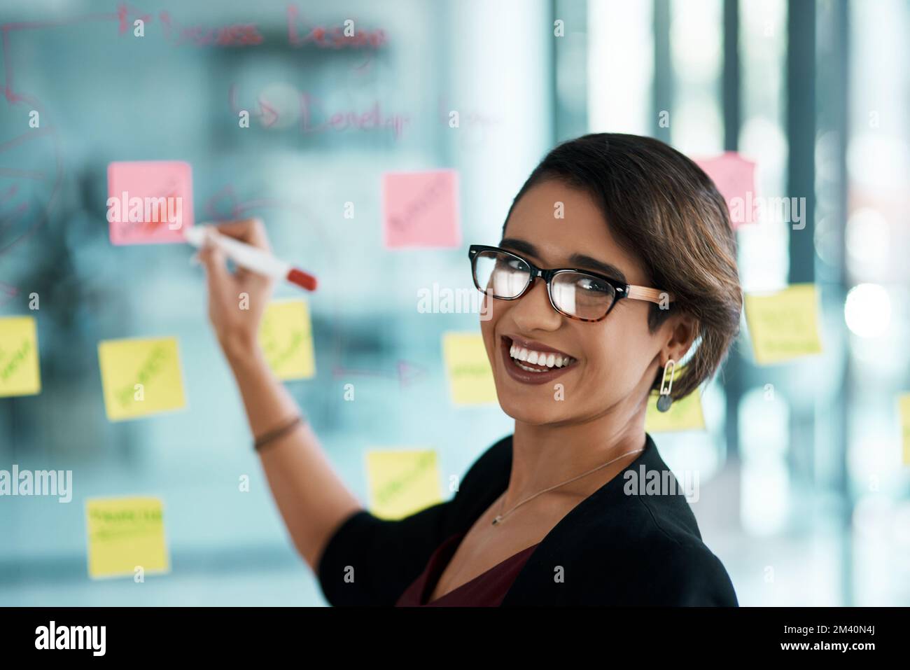 Post-its everywhere. an attractive young businesswoman standing alone ...