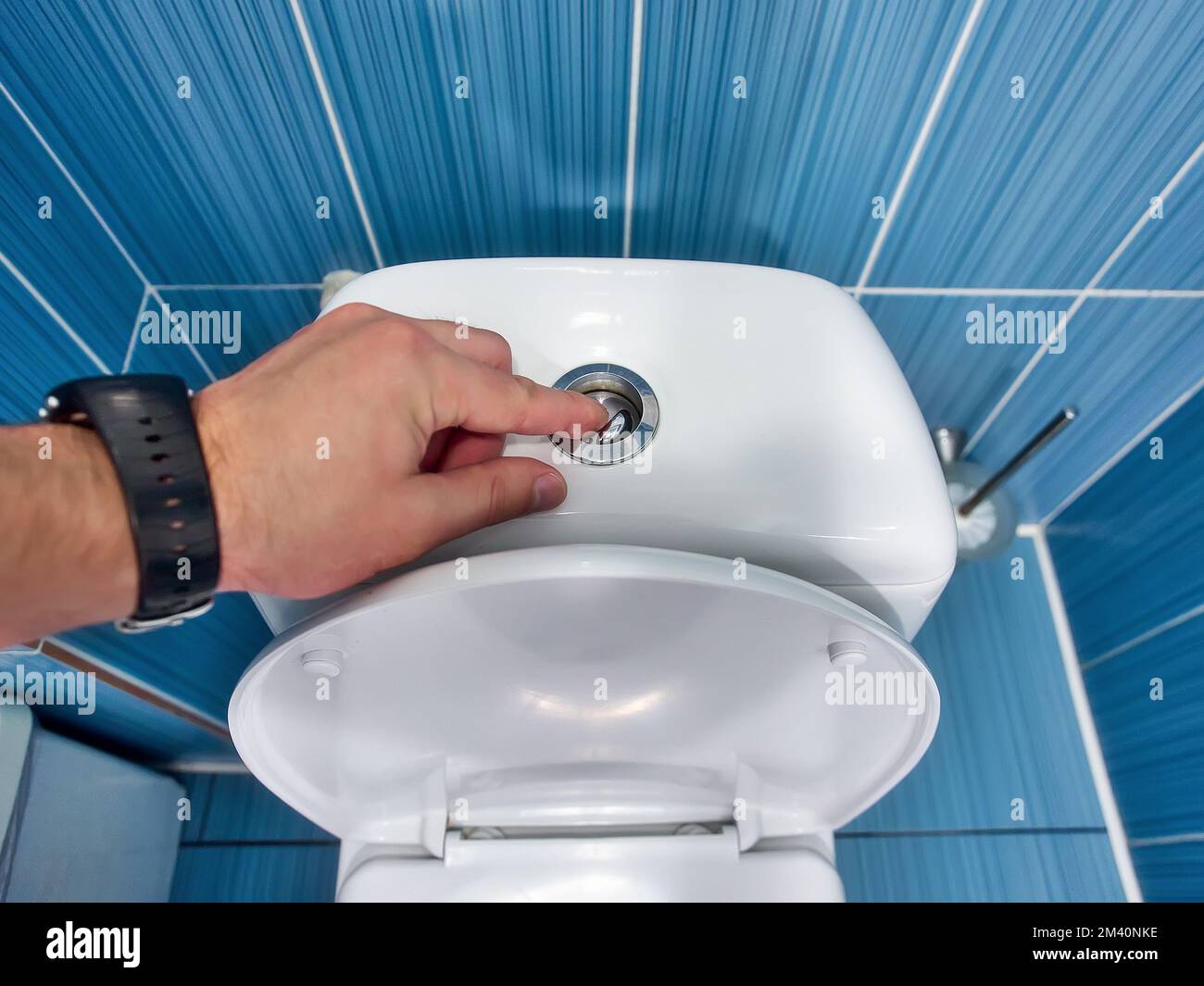 Man presses toilet button with his hand and drains water in toilet ...