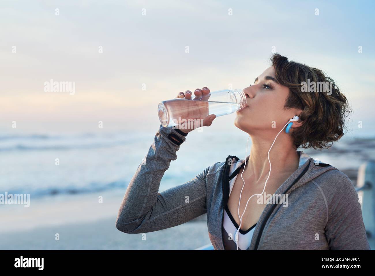 Take a sip and go again. a young woman drinking water after her run ...
