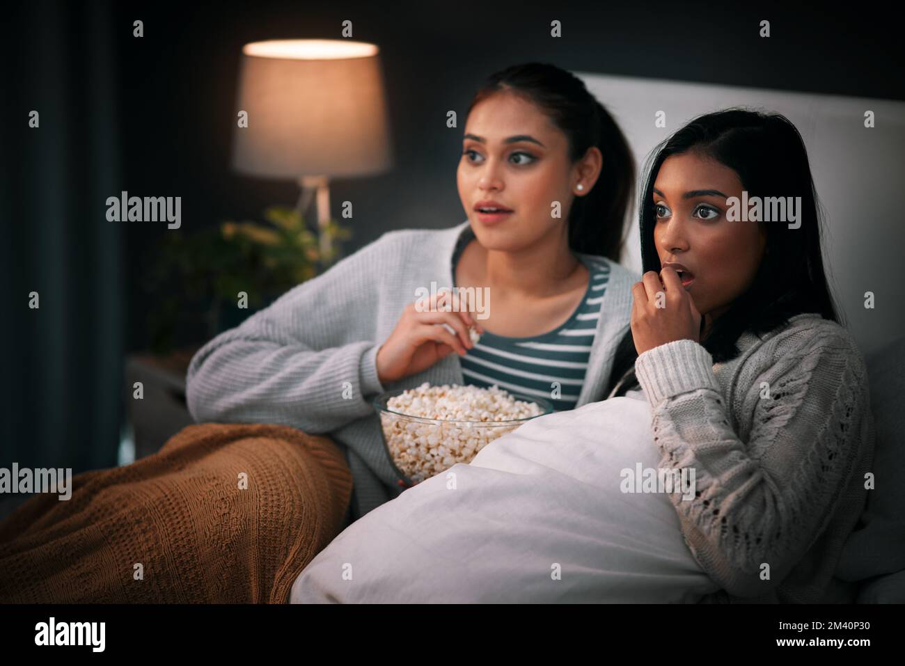 Glued to the screen with great entertainment. two young woman eating ...