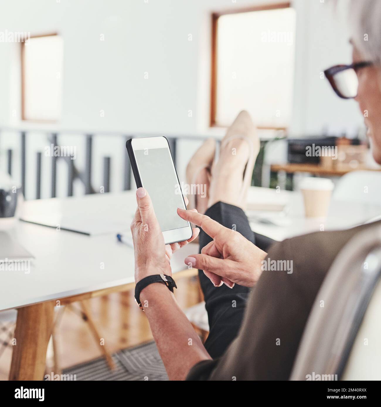 Kicking back. Rearview shot of an unrecognizable mature businesswoman ...