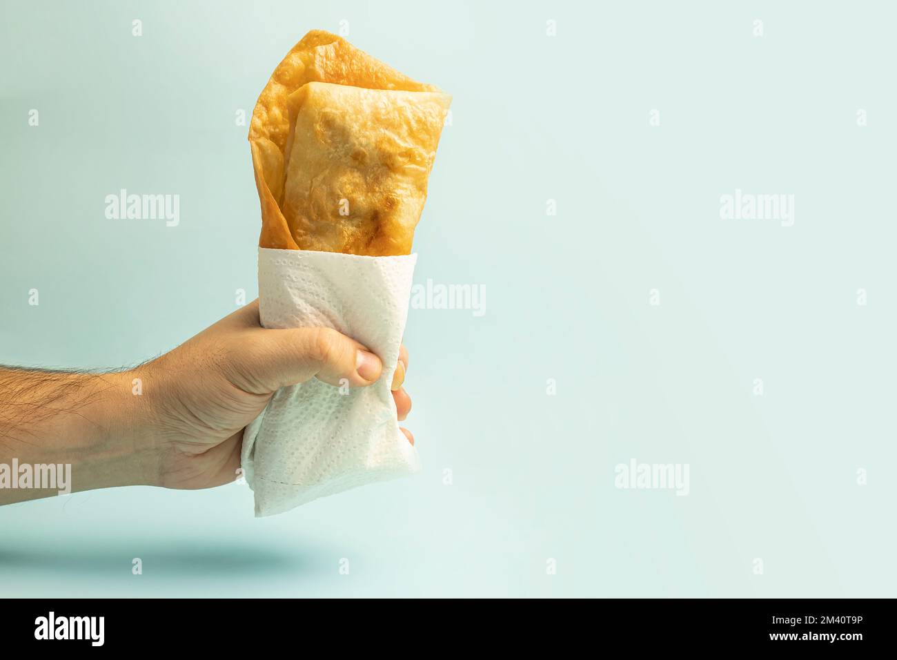 shawarma in a male hand blue background. copy space Stock Photo - Alamy