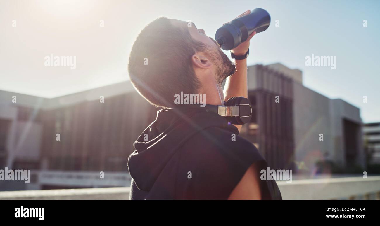 Hydration is a must for good health. a young man drinking water during ...