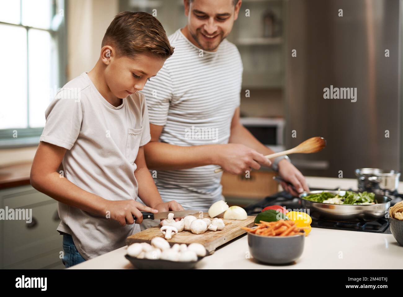 Little chef in the making. a young boy helping his father cook in the ...