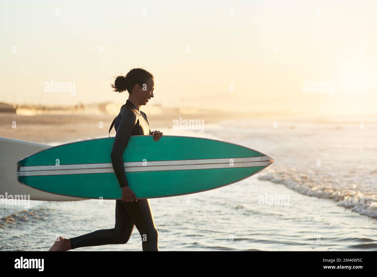 The sea sets her free. a cheerful young woman going surfing at the ...