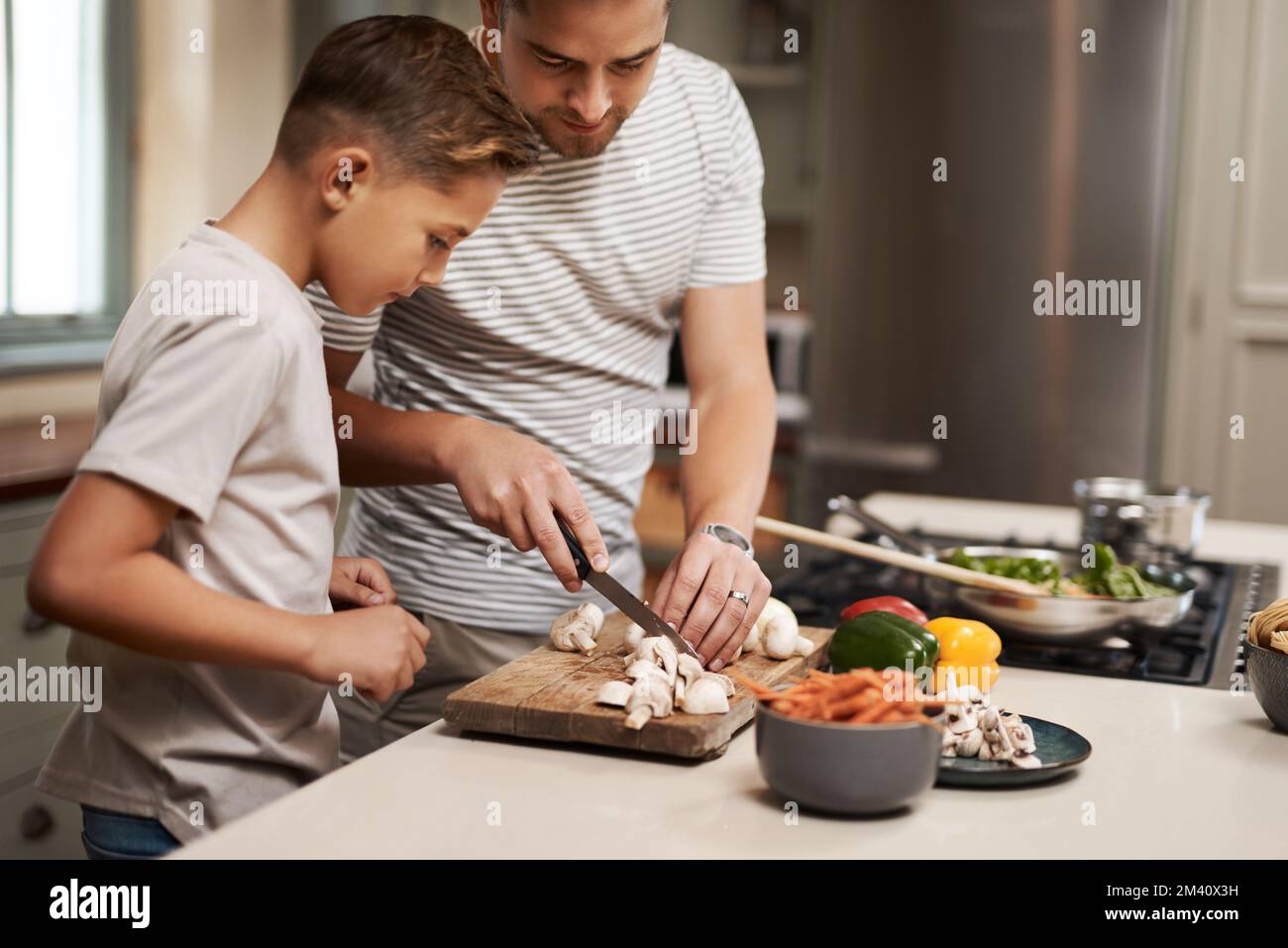 I need you to slice them this thin. a young boy helping his father cook ...