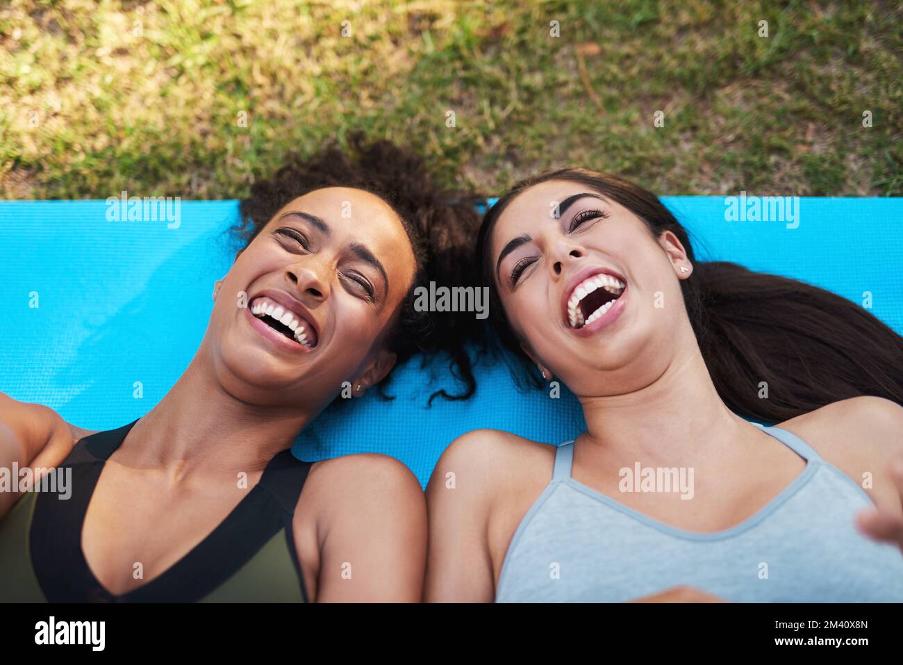 Laughing burns calories too. two attractive young women lying down on a ...