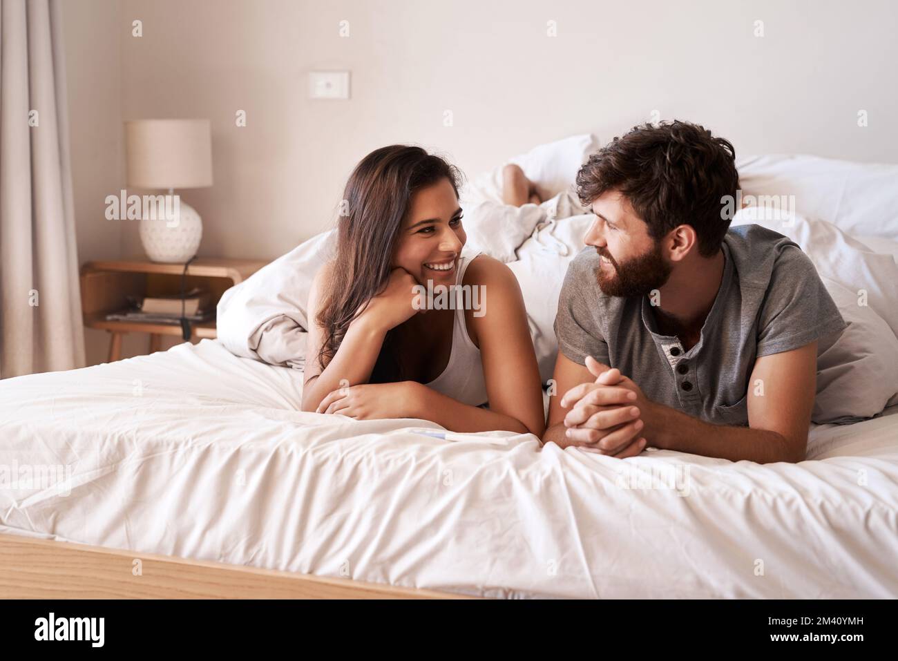 Never stop getting to know each other. a happy young couple chatting in bed at home Stock Photo ...