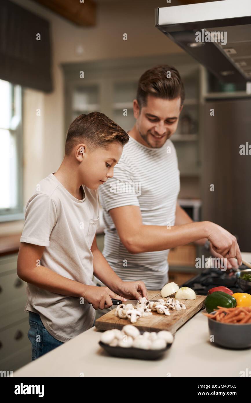 Youre doing great, bud. a young boy helping his father cook in the ...