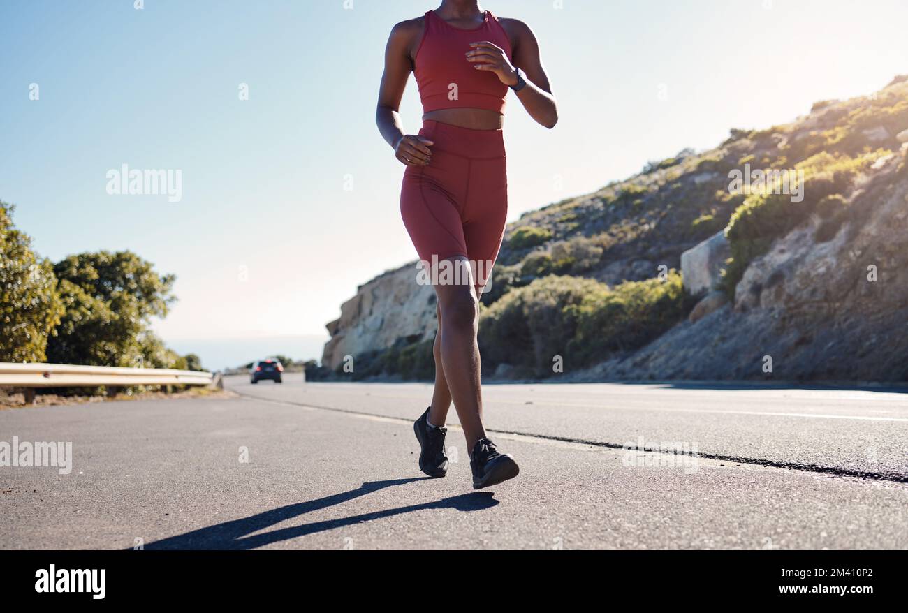 Fitness, exercise and legs of black woman running on road outdoors for ...