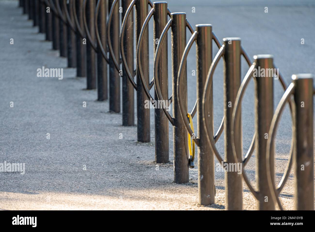 A symmetric line of metallic railings for bicycles on an asphalt road ...