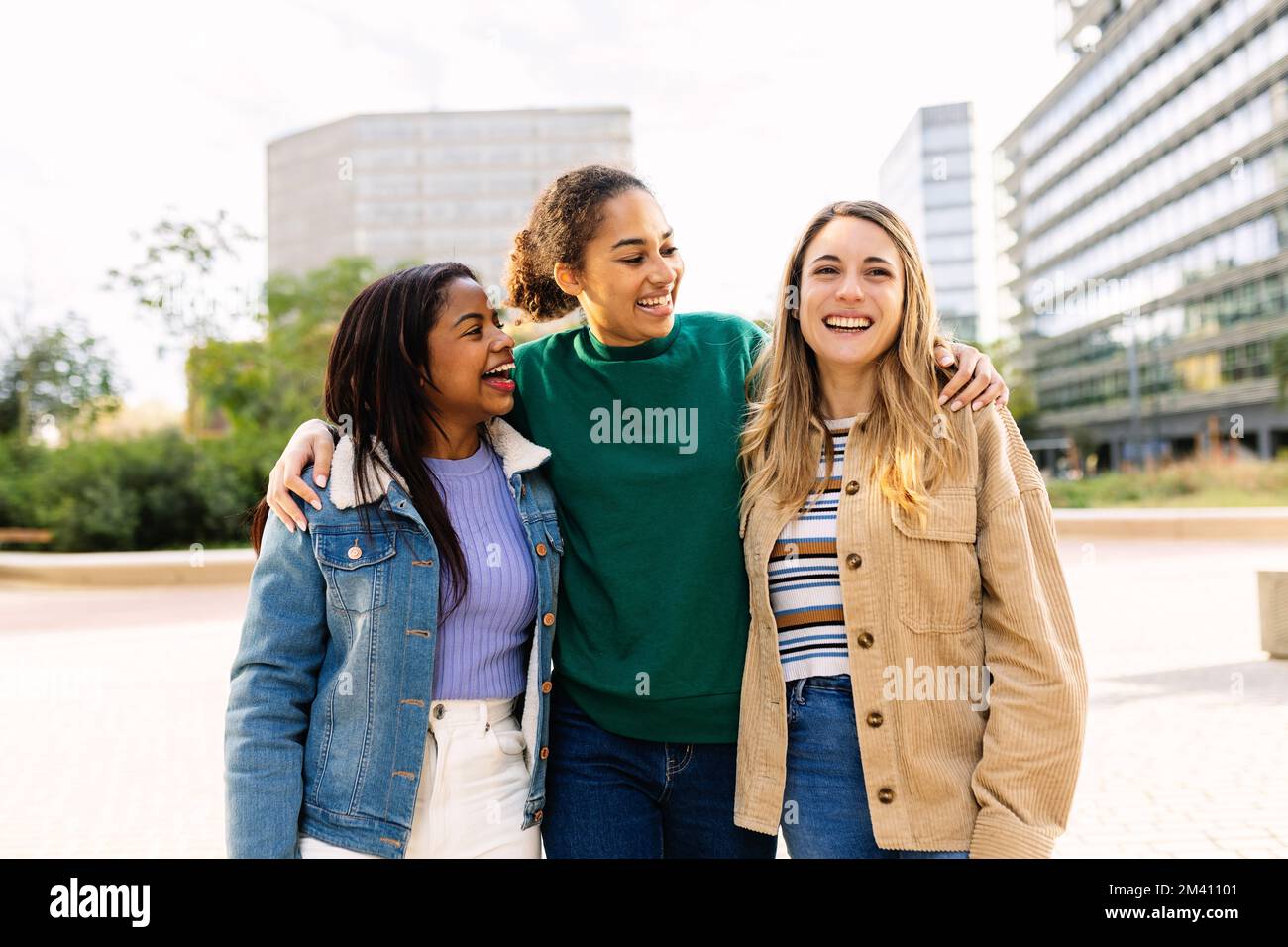 Three happy multiracial young women friends laughing outdoors Stock ... Three happy multiracial young women friends laughing outdoors Stock ...