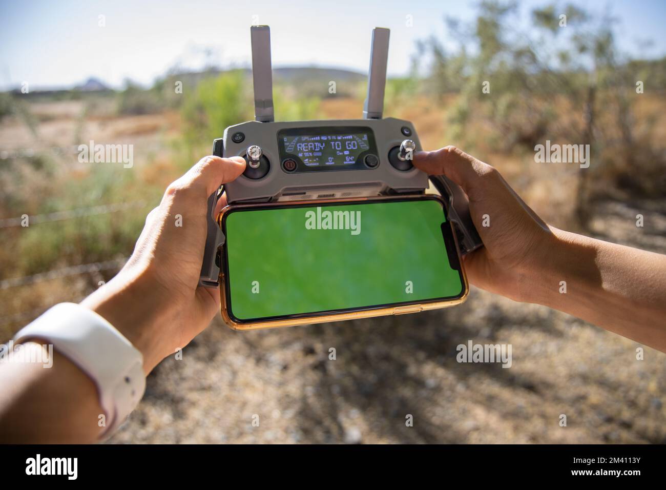 A closeup shot of adult hands holding a drone controller with green ...
