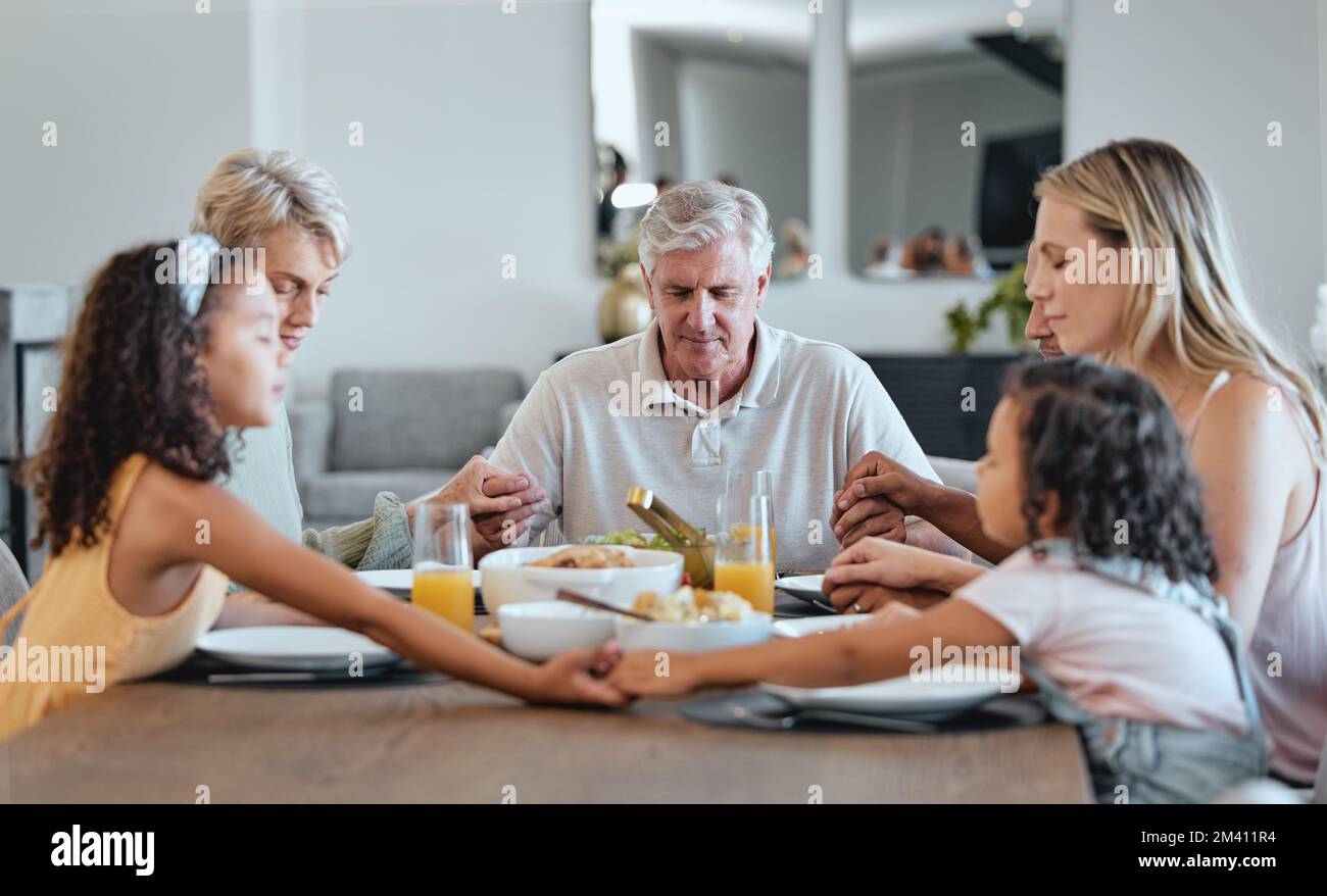 Family, food and holding hands for prayer together at dining room table ...