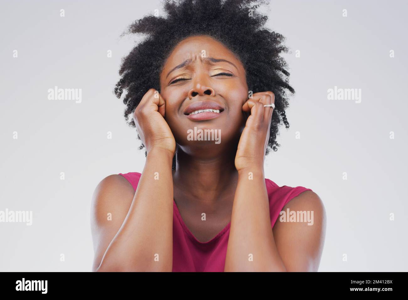 I cant hear what youre saying. Studio shot of a young woman crying ...