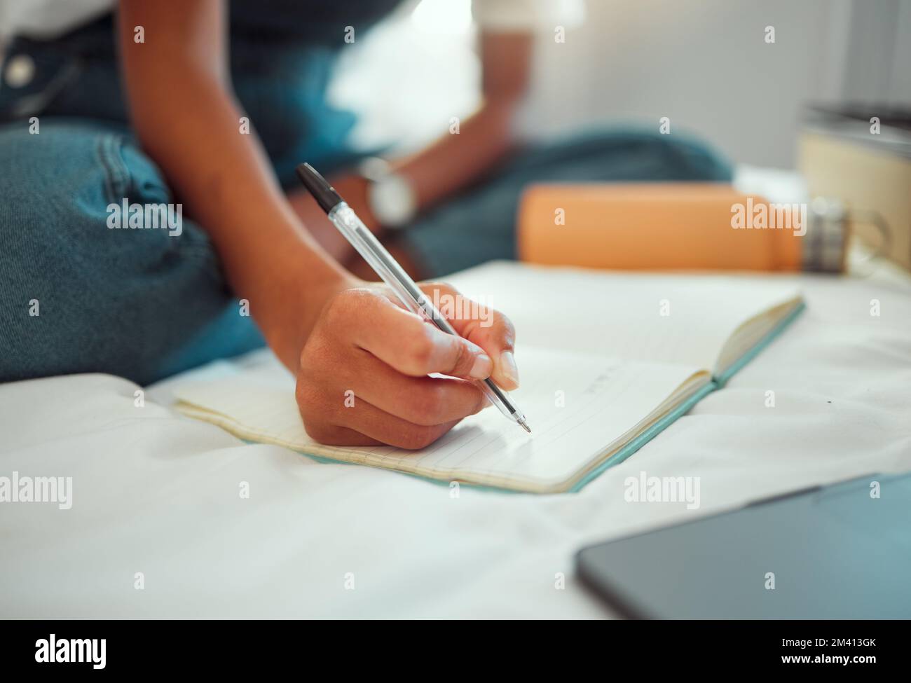 Notebook, bed and hands of student writing homework, research project ...