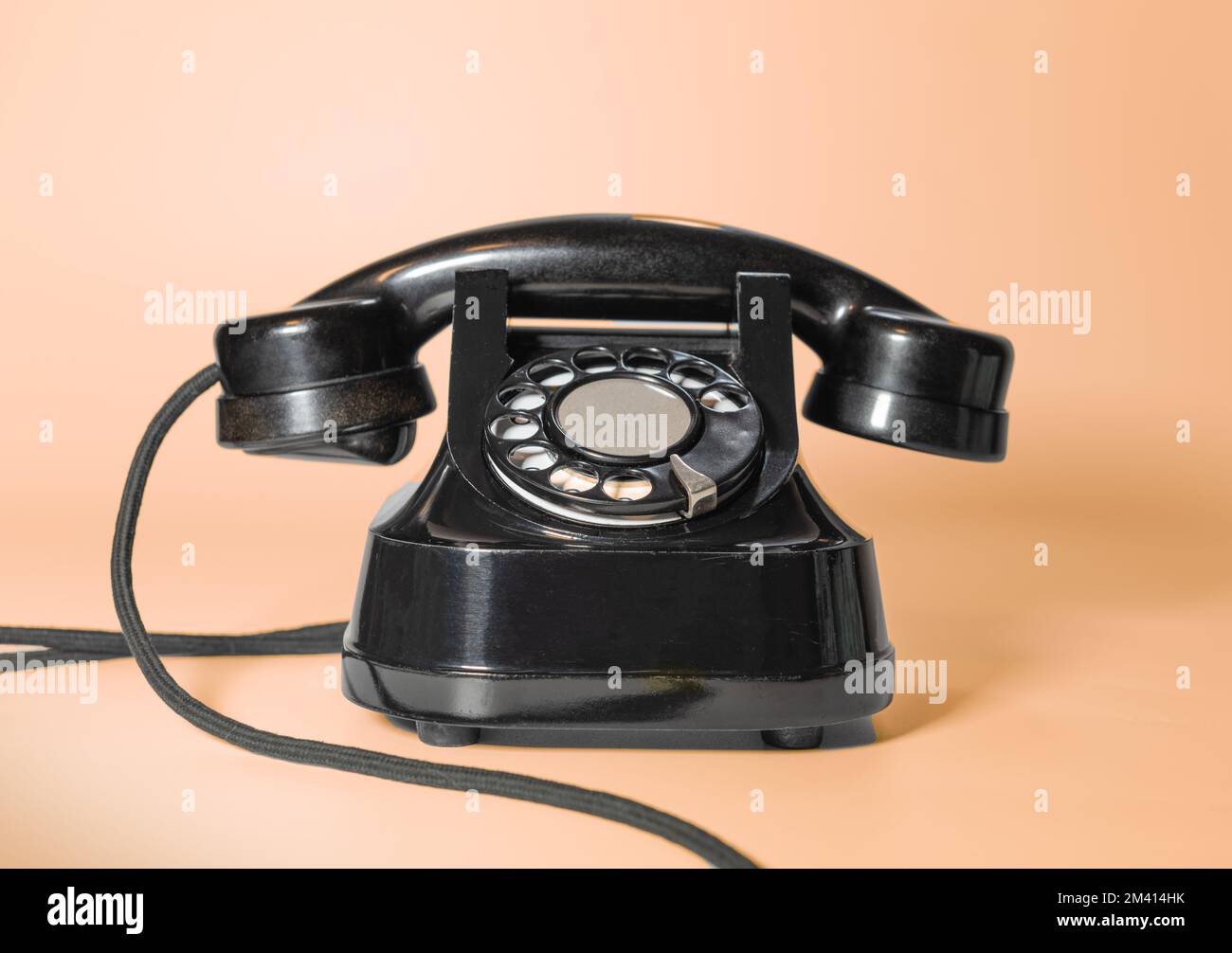 old rotary black telephone with traces of time. on a peach background ...